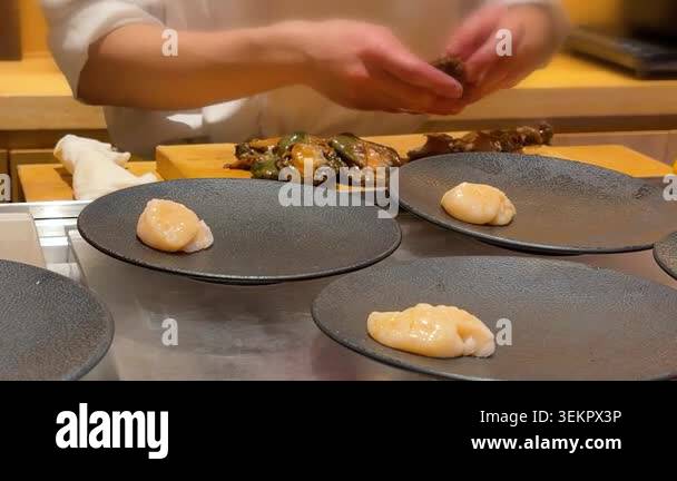 Professional Japanese chef prepping raw seafood on cutting board in ...