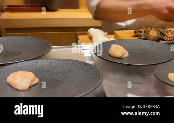 Professional Japanese chef prepping raw seafood on cutting board in ...