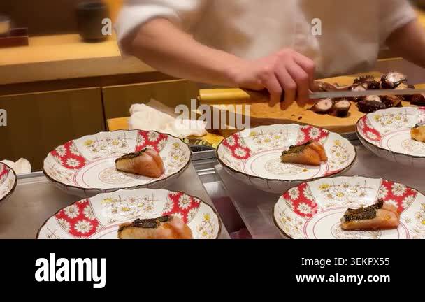 Chef slicing boiled octopus tentacle on wooden board in a high-end ...