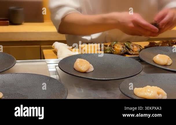 Professional Japanese chef prepping raw seafood on cutting board in ...