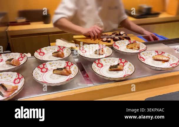 Chef slicing boiled octopus tentacle on wooden board in a high-end ...
