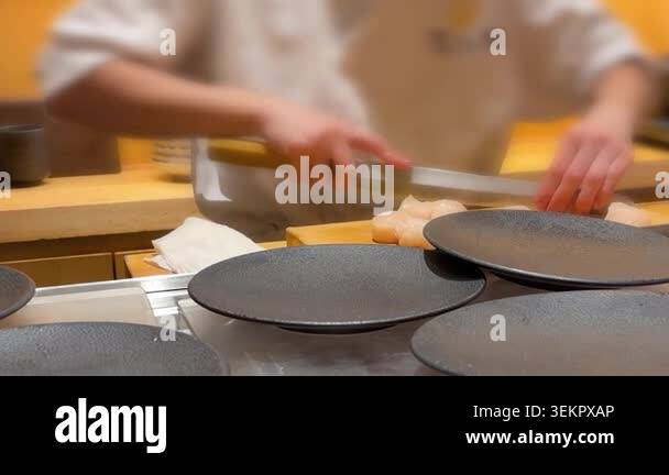 Professional sushi chef prepares fresh raw scallops at an authentic ...