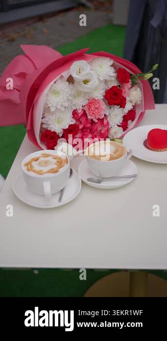 Romantic table in a cafe with two cappuccinos, a bouquet of flowers and ...