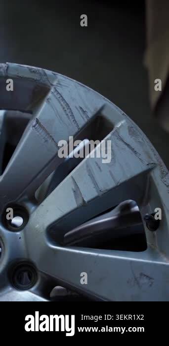 Damaged silver alloy wheel with scratches and scuffs before repair and ...