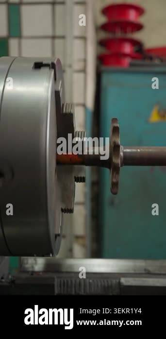 Metal shaft fixed in an industrial lathe chuck inside a workshop for ...
