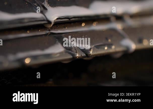 Soap suds and water drops on a glossy black car body during a detailed ...