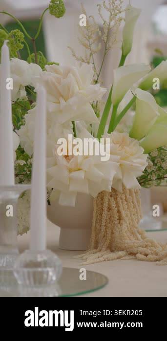 White floral centerpiece with roses, calla lilies, candles and a ...