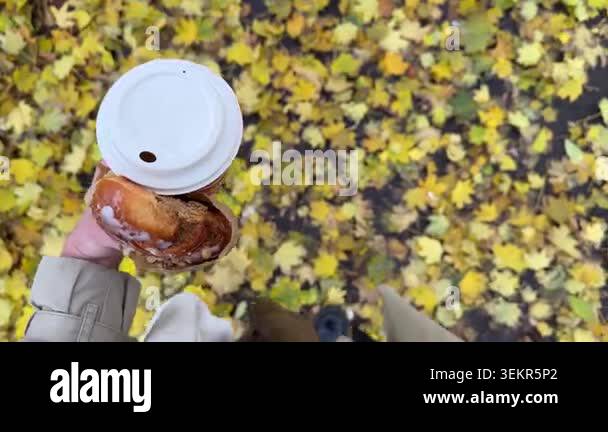 Woman hand with fresh pastry from bakery and hot coffee to go in paper ...