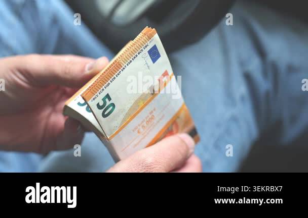 Detailed video footage of a person holding a thick pack of fifty euro ...