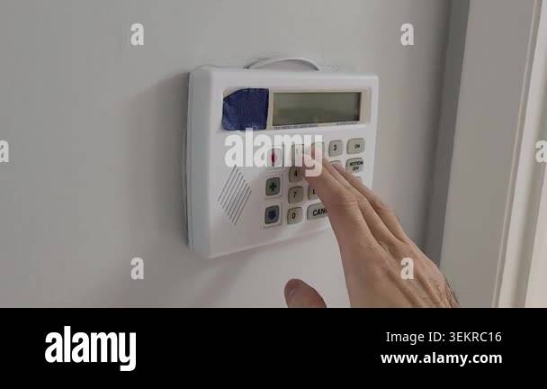 Home security alarm keypad with hand entering access code on wall ...