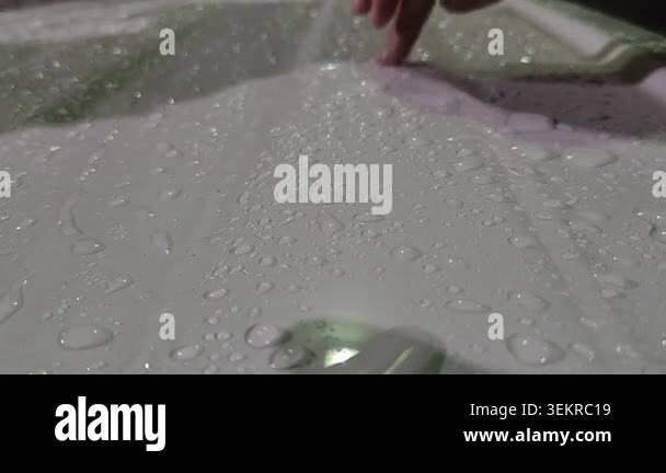 Detailed close-up of water droplets spread across a vehicle surface ...