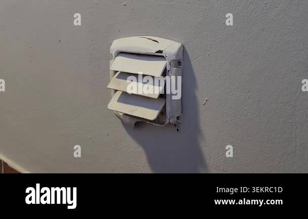 Close-up of a weathered white plastic wall vent cover with visible ...