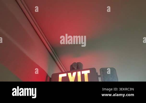 Indoor illuminated emergency exit sign attached above a doorway ...