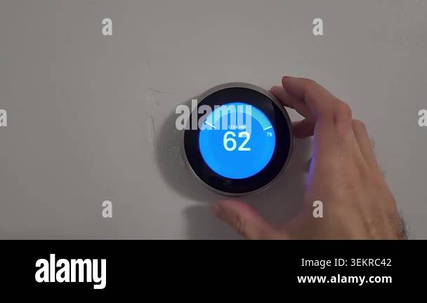 Hand adjusting smart thermostat temperature on wall mounted controller ...