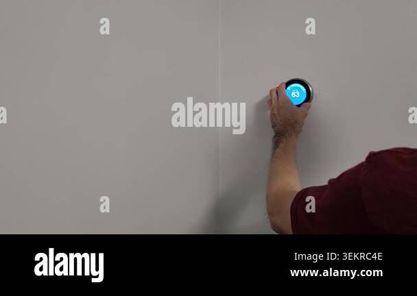 Video footage showing a person operating a smart thermostat mounted on ...