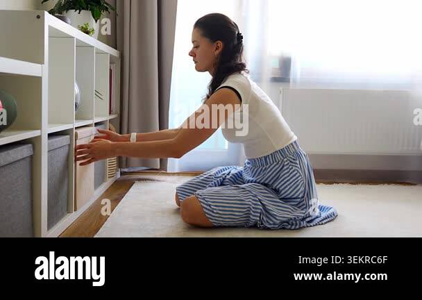 Young woman using storage box from shelving system in home interior ...