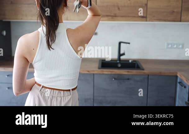 Young woman standing in modern apartment kitchen and holding house keys ...
