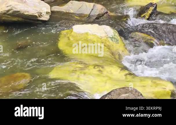 Close up of a fast flowing mountain river water moving over colorful ...