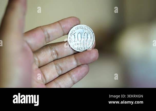 Hand holding a vintage 100 rupiah coin with detailed classic Indonesian ...