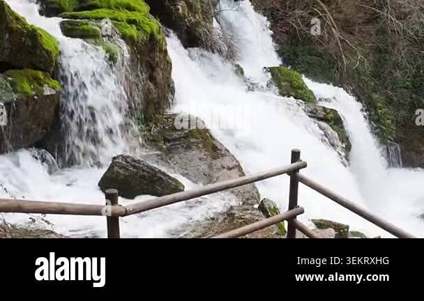 A real-time footage of a majestic mountain waterfall cascading over ...