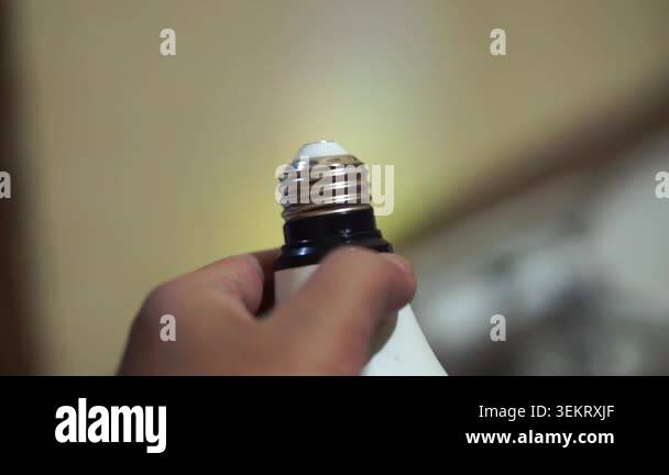 Close up of an LED lamp fitting with a metal screw base held in hand ...