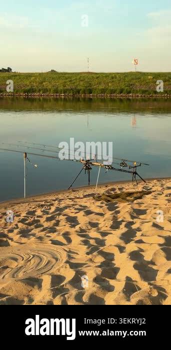 Fishing rods set up on sandy bank of Elbe River in Germany, ready for ...