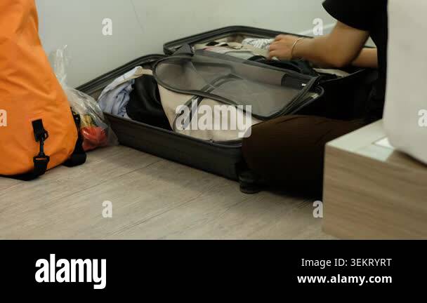 Happy Asian traveler packing luggage in bedroom before journey ...