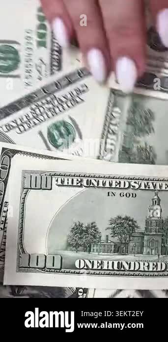 Hands are seen organizing and counting one hundred dollar bills in a ...