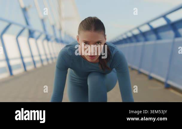 Closeup footage of focused young female athlete in crouched runners ...