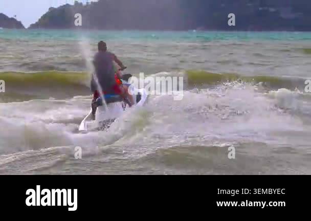 Jet ski rider jumping waves at tropical beach with strong surf ocean ...