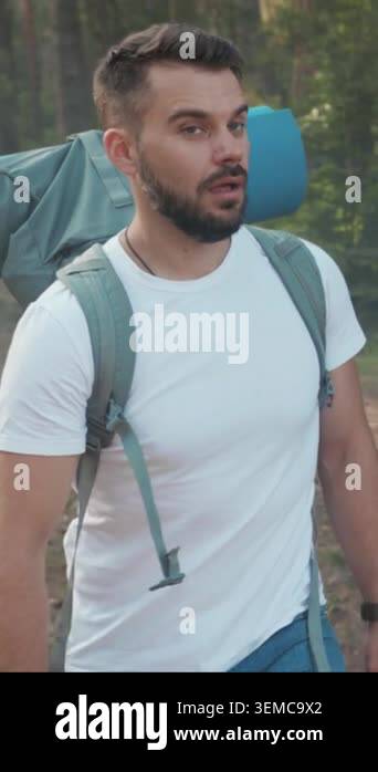 Caucasian backpacker smiling in forest, confident posture with hands on ...