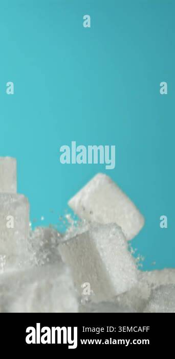 Cubes of sugar fly up and fall down on a blue background. Filmed on a ...