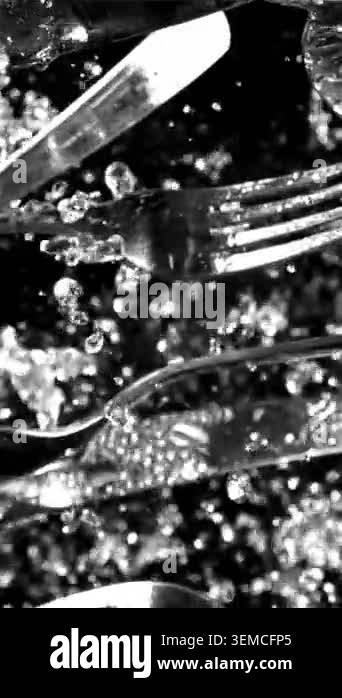 Cutlery flies up with splashes of water. View from above. Filmed on a ...