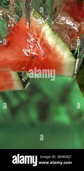 Watermelon slices fall under the water. Filmed on a high-speed camera ...