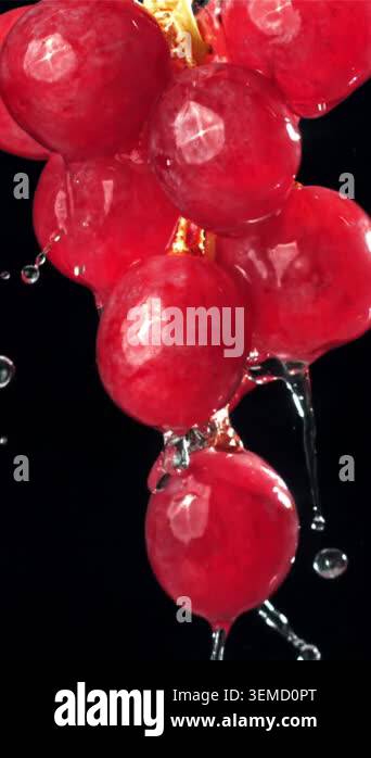 Raindrops falling on red grapes on black background. Filmed on a high ...