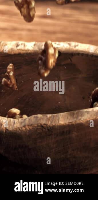 Walnuts fall into a wooden bowl. Filmed on a high-speed camera at 1000 ...
