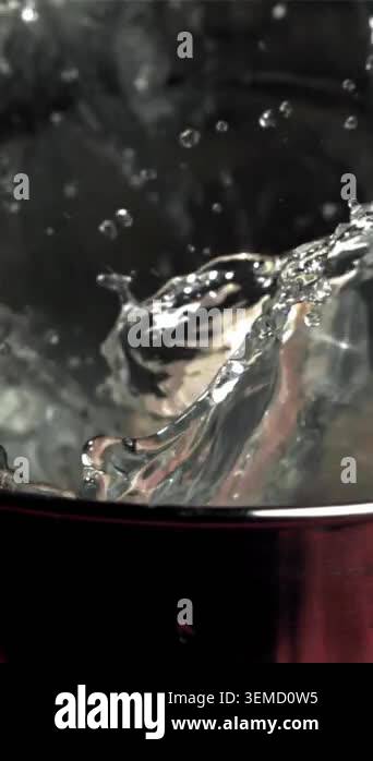 Raw chicken legs fall into a pot of water. Filmed on a high-speed ...