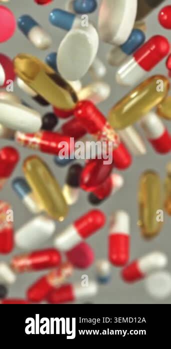 Dense cluster of assorted pills and capsules suspended against neutral ...