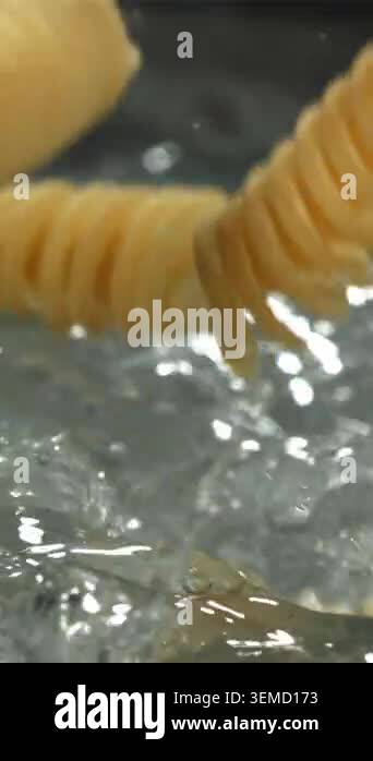 Fusilli pasta falls into boiling water. Filmed on a high-speed camera ...