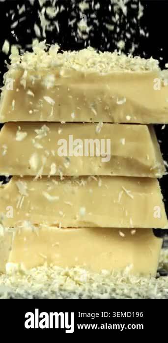 Shredded white chocolate falls on a tower of chocolate pieces. Filmed ...