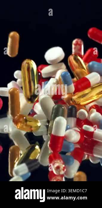 Vibrant colorful capsules and tablets collide in midair against dark ...