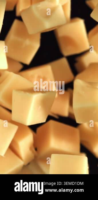 Maasdam cheese flies up and falls down on a black background. Filmed on ...