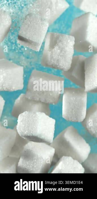 Cubes of sugar fly up and fall down on a blue background. Filmed on a ...