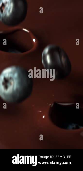 Blueberries fall into chocolate. Filmed on a high-speed camera at 1000 ...