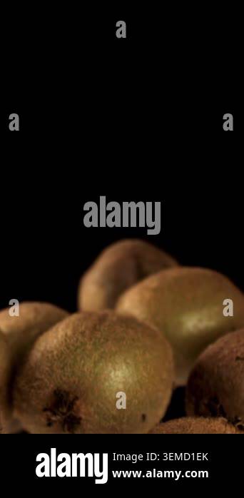 Whole kiwis fly on a black background. Filmed on a high-speed camera at ...
