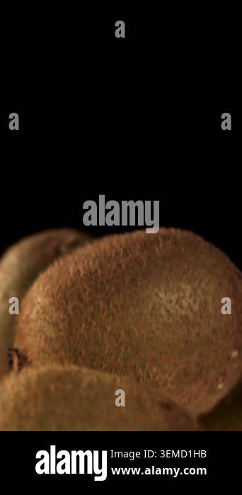 Whole kiwis fly on a black background. Filmed on a high-speed camera at ...