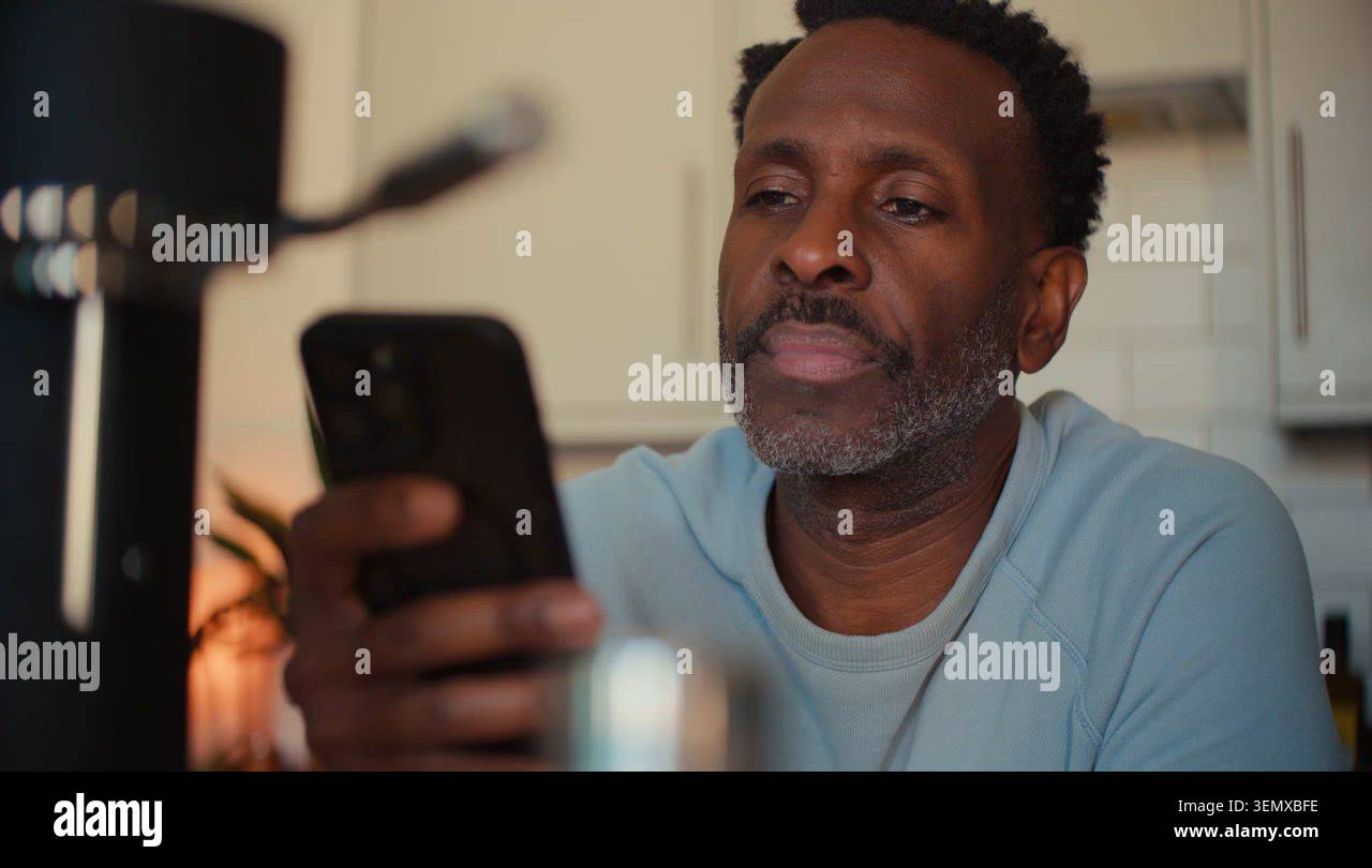 Man cracking a smile while looking at his phone in a kitchen Stock ...