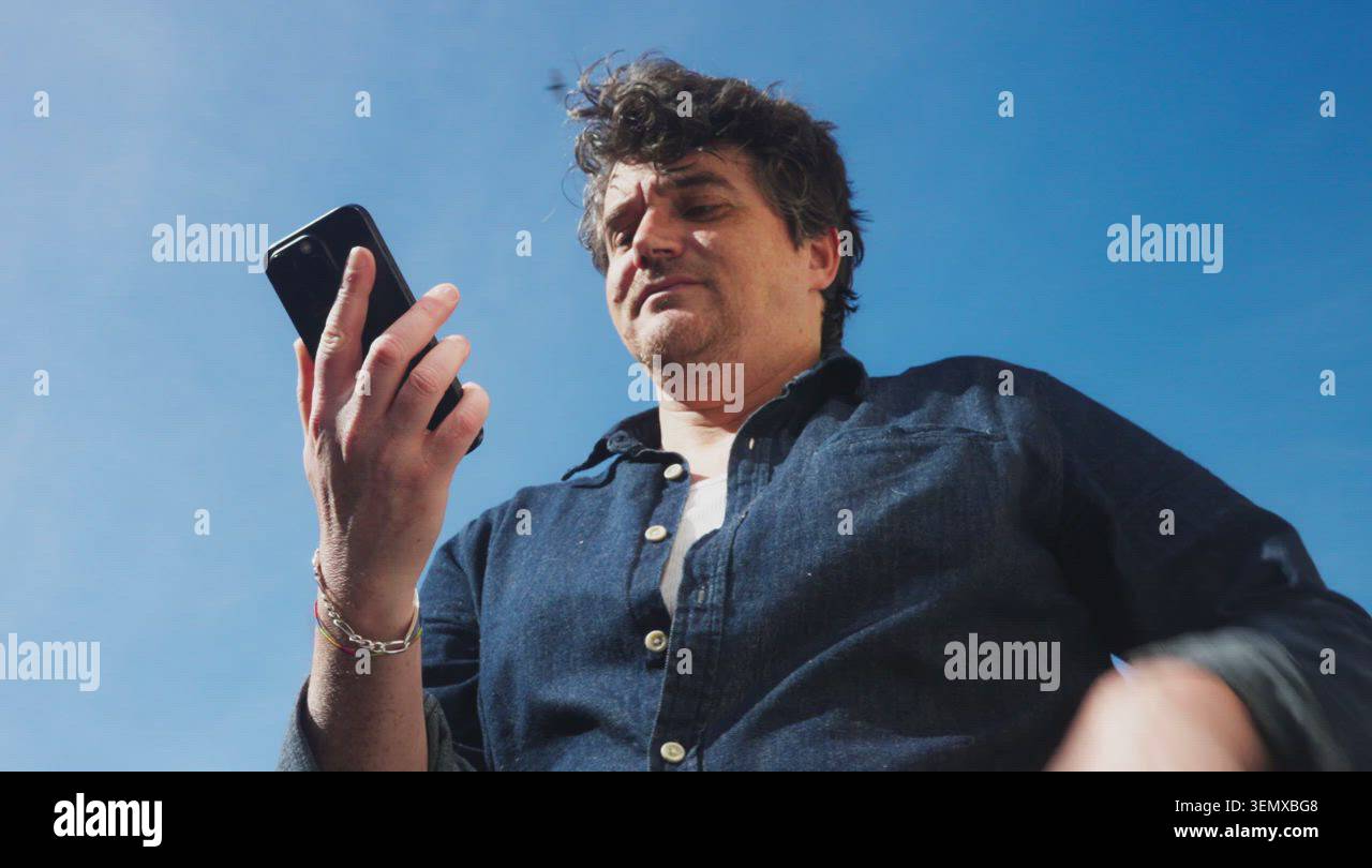 Man Looks at Phone Under Clear Sky While Standing Outdoors Stock Video ...