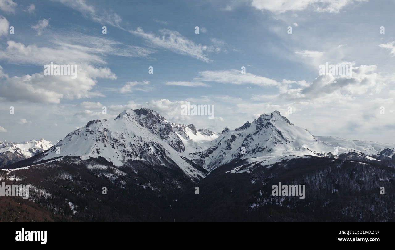 Snowy twin peaks Mountains Under a Cloudy Sky, drone footage Stock ...