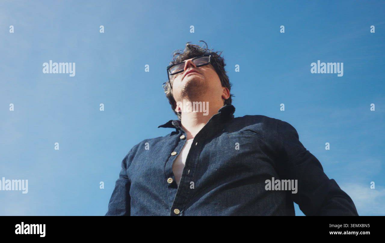 Man with eyeglasses Looks up at Blue Sky During Sunny Day in Open Area ...